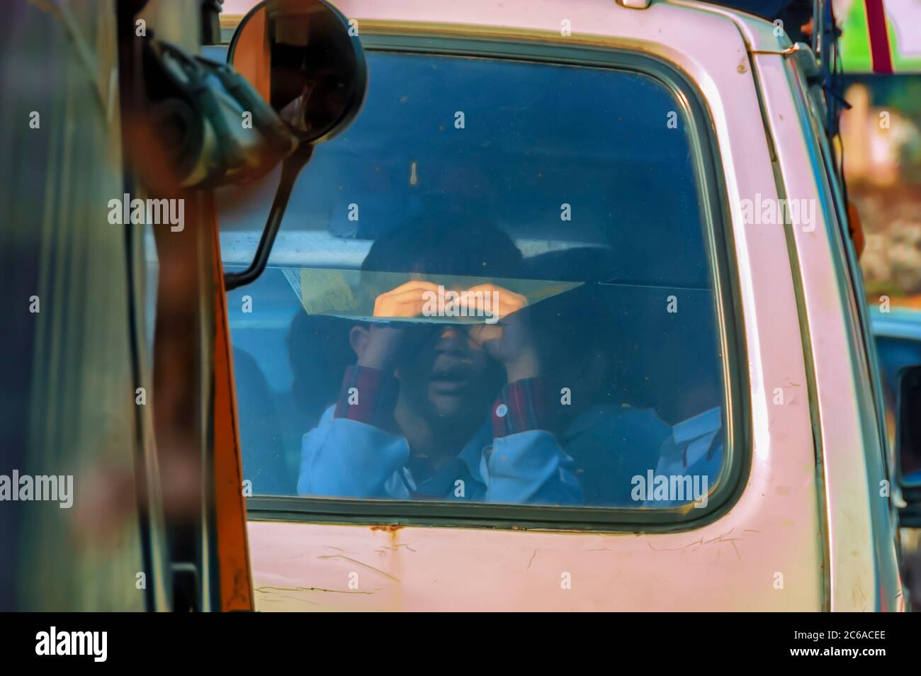 A school kid inside a school van using his hands as a binocular while ...