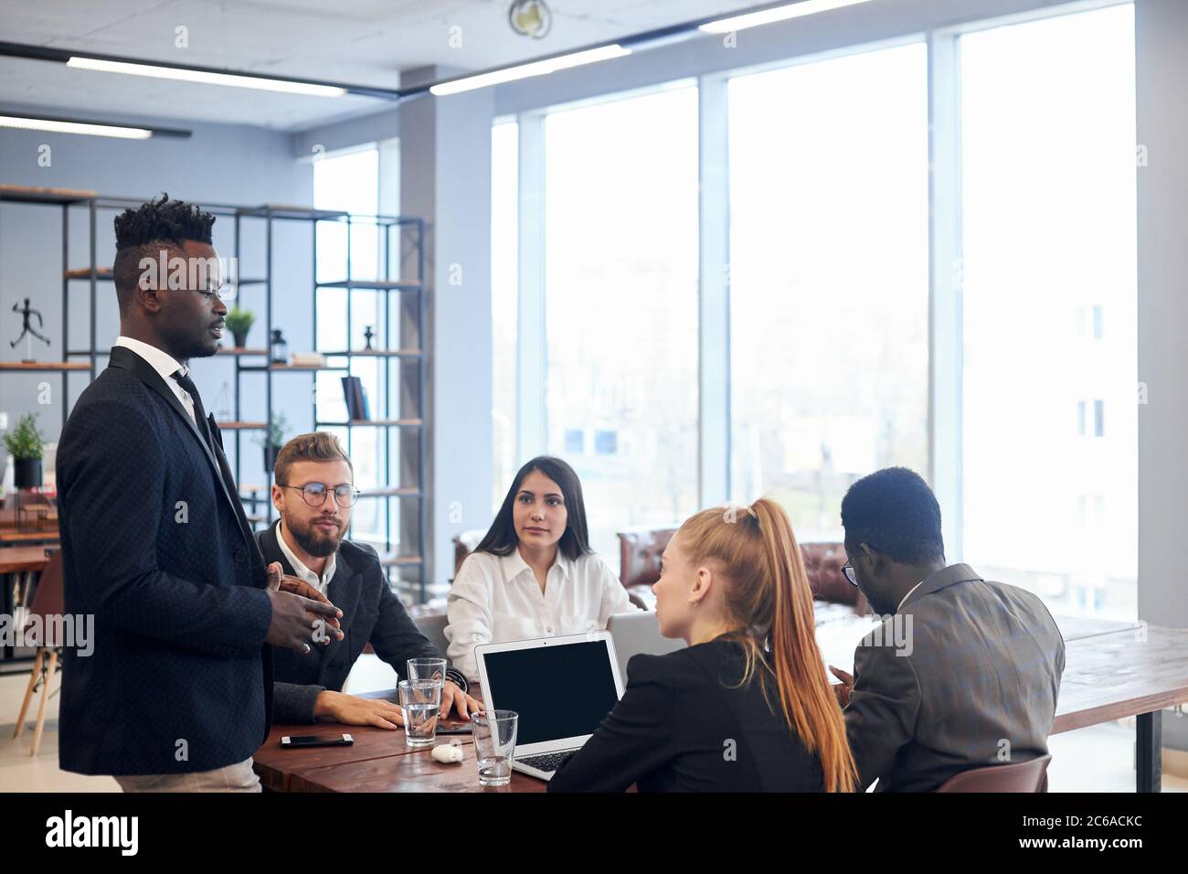 Personable black employee explains to foreign colleagues new client ...