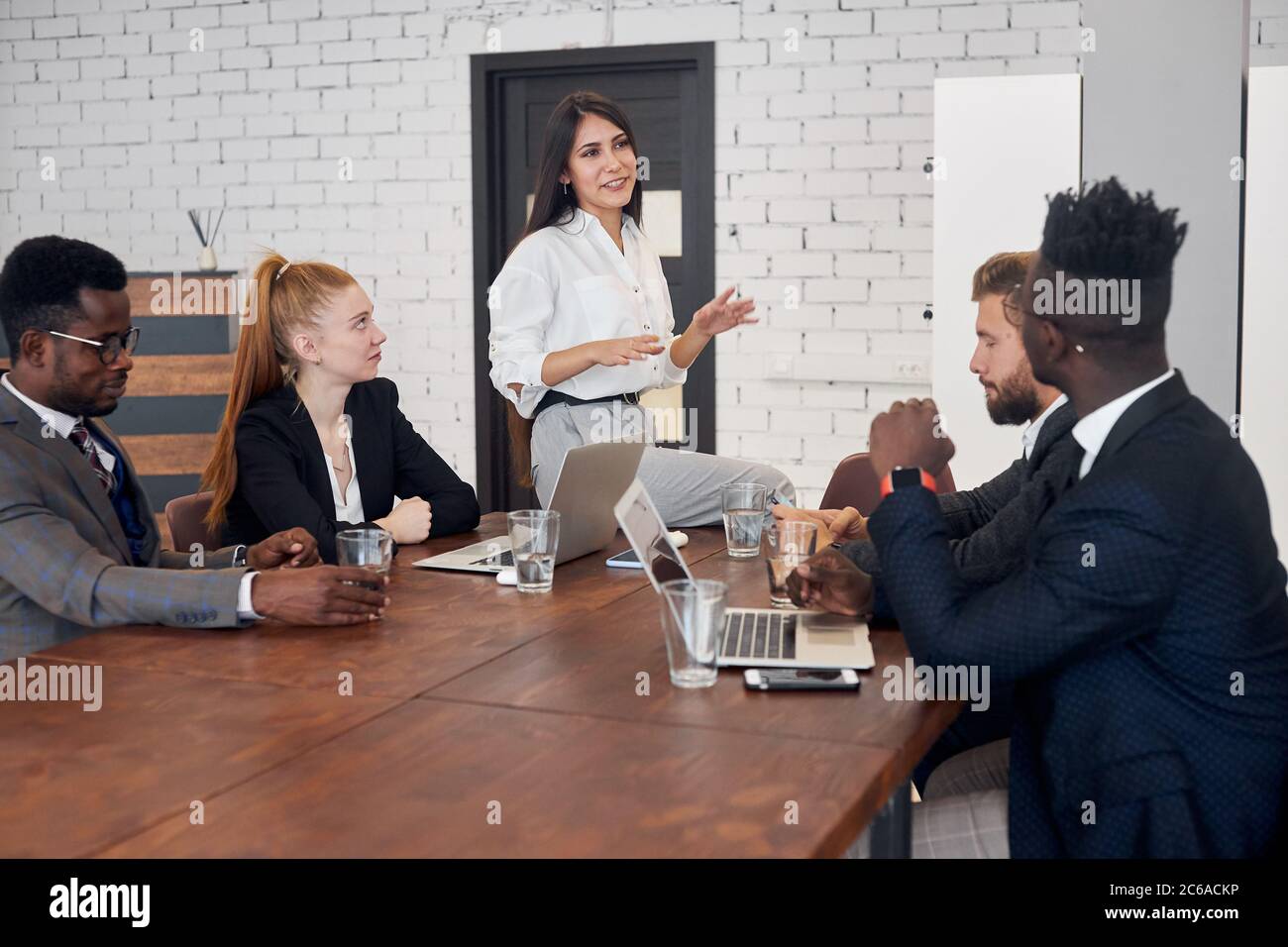 caucasian female brunette sit on table talking with african and ...