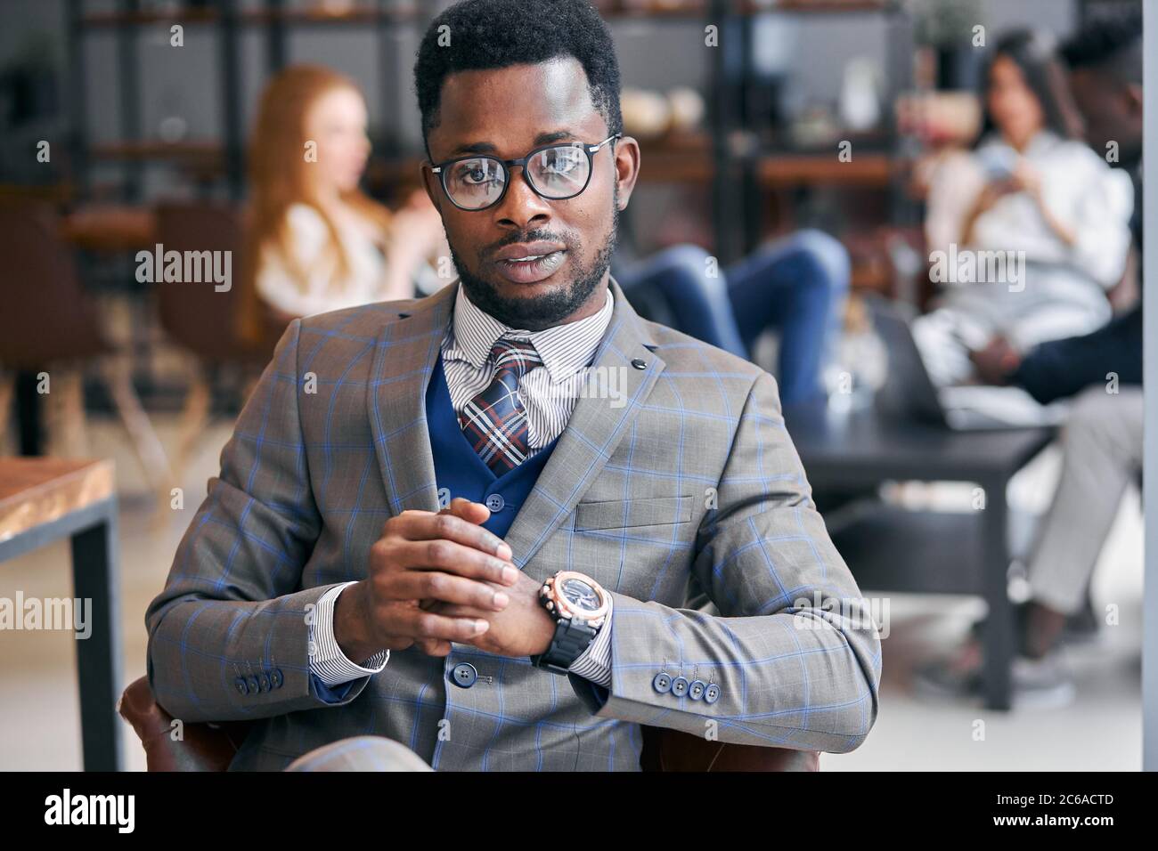 Sedate black man in grey tuxedo and eyeglasses sit looking at camera ...