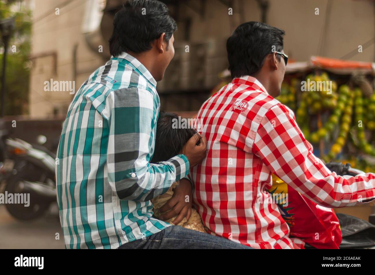 Three riders on a motorbike. A girl child is asleep while riding ...