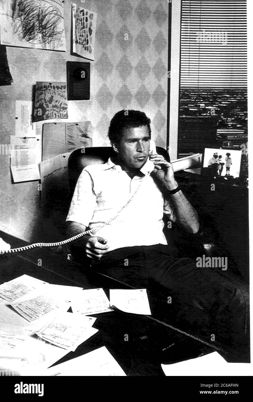 George W. Bush talks on the telephone at his office desk at Arbusto ...