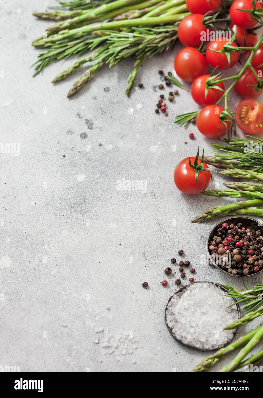 Light food background with healthy organic cherry tomatoes, asparagus and rosemary with bowl of ...