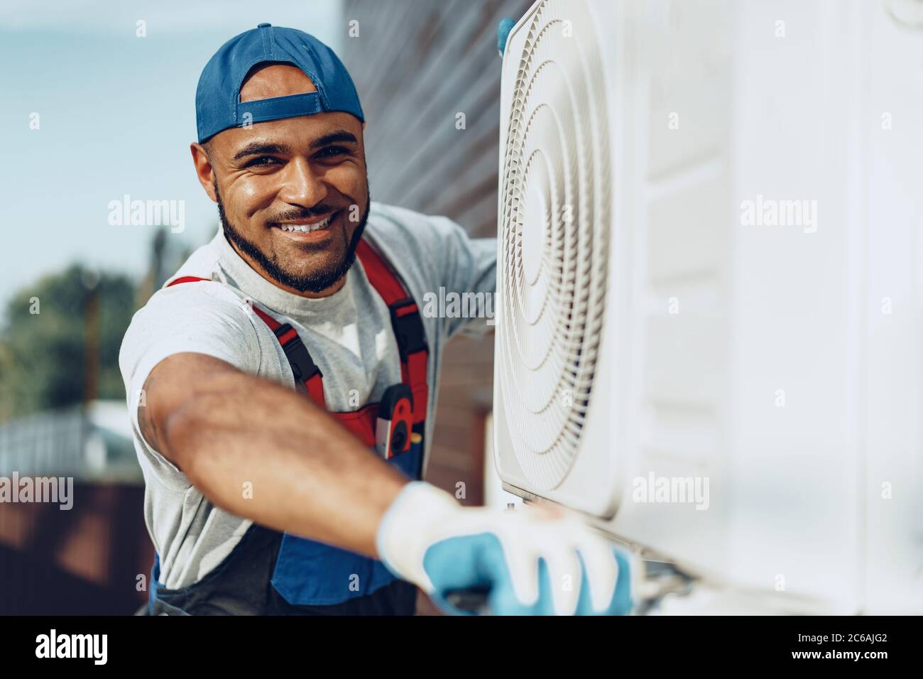 Young black man repairman checking an outside air conditioner unit ...