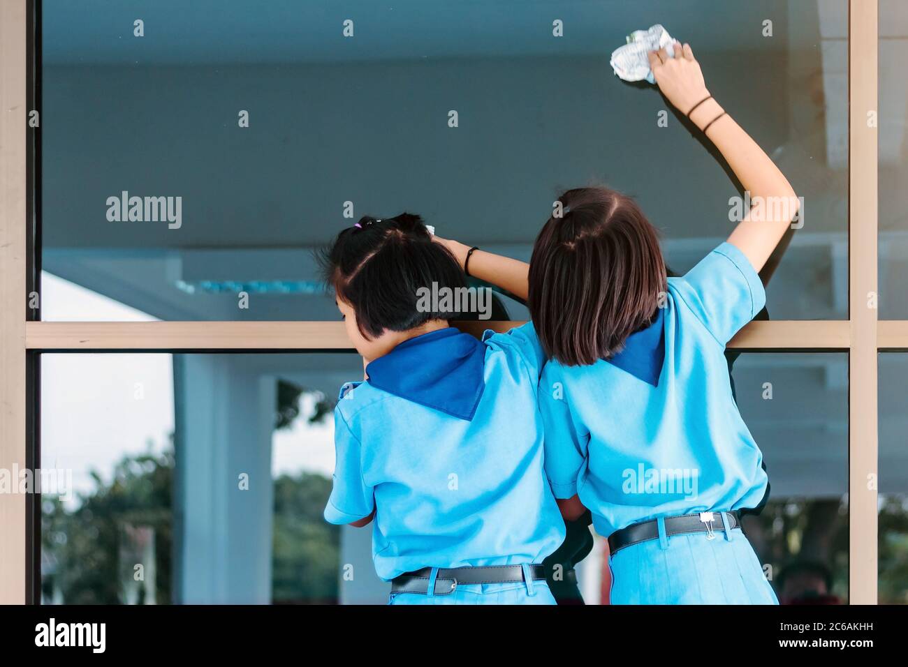 Back view of female students are helping to wipe the glass with wet ...
