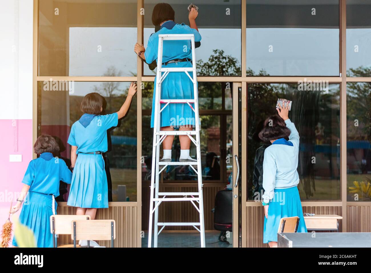 Back view of female students are helping to wipe the glass with wet ...