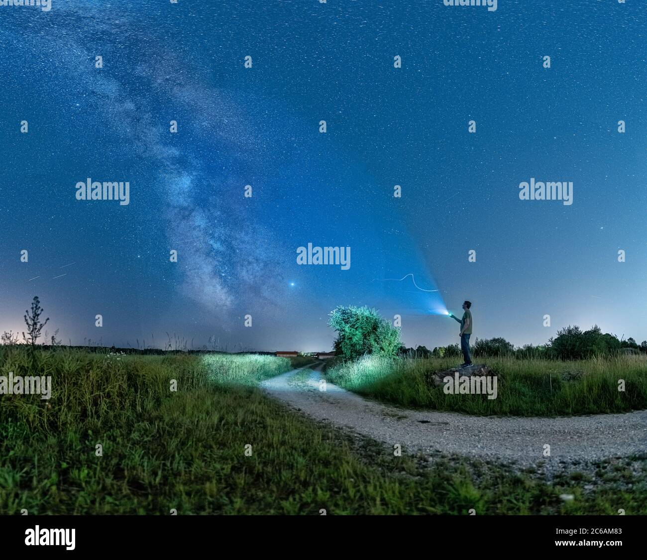 Man with a lamp standing on a trunk is watching for the night sky milky ...