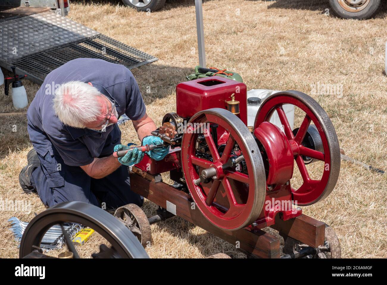 An enthusiast maintaining a vintage stationary engine displayed at a ...