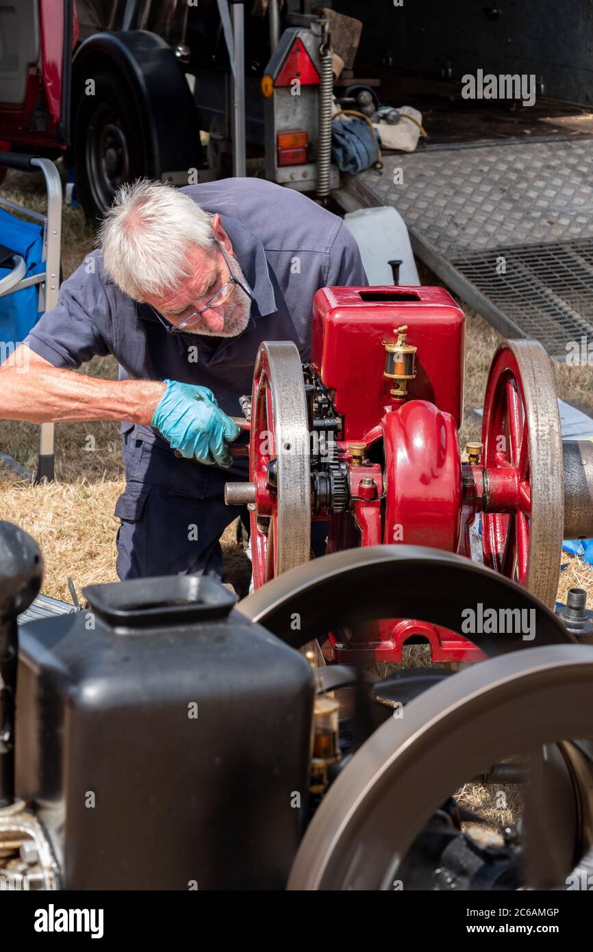 An enthusiast maintaining a vintage stationary engine displayed at a ...