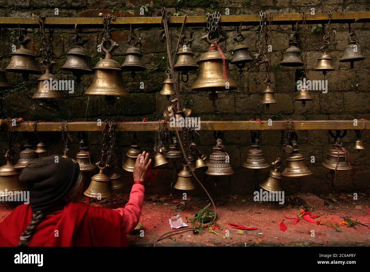 Elderly Nepalese woman touches the ghanta (Hindu ritual bell) installed ...