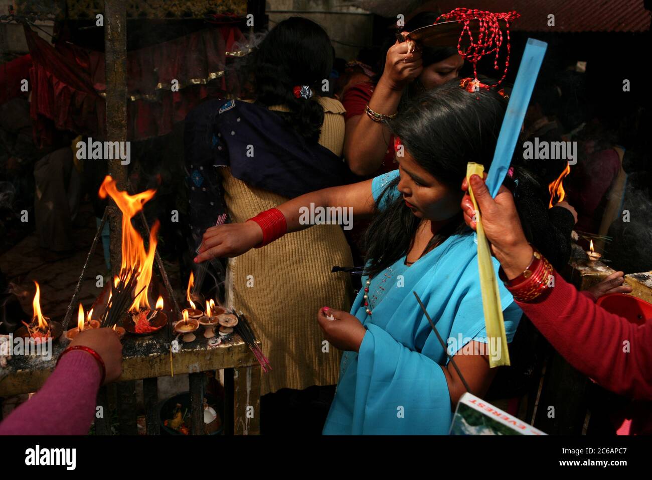 Nepalese women lit incense sticks from ritual oil lamps in the main ...