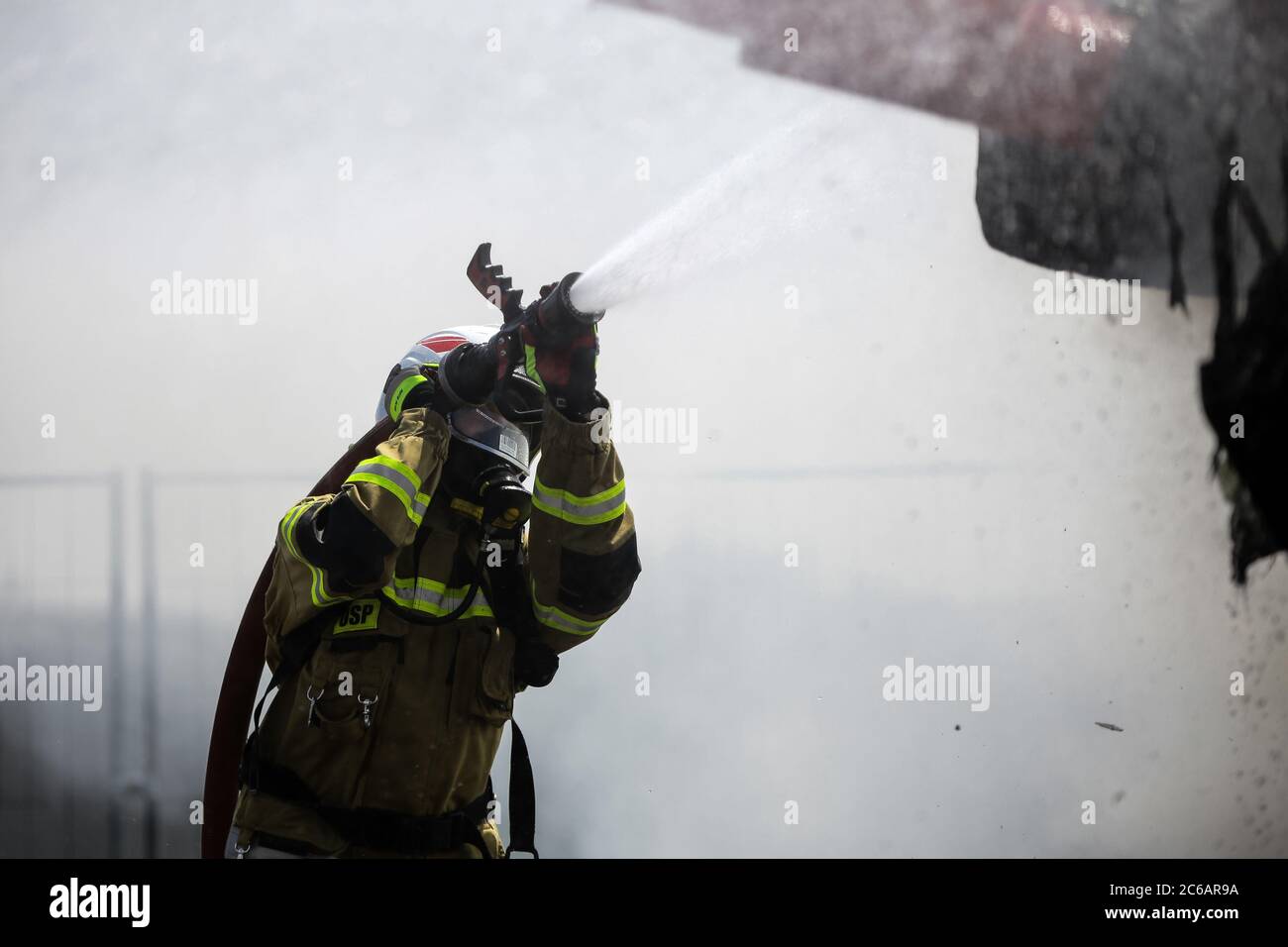A firefighter in heavy equipment putting out the fire during the ...