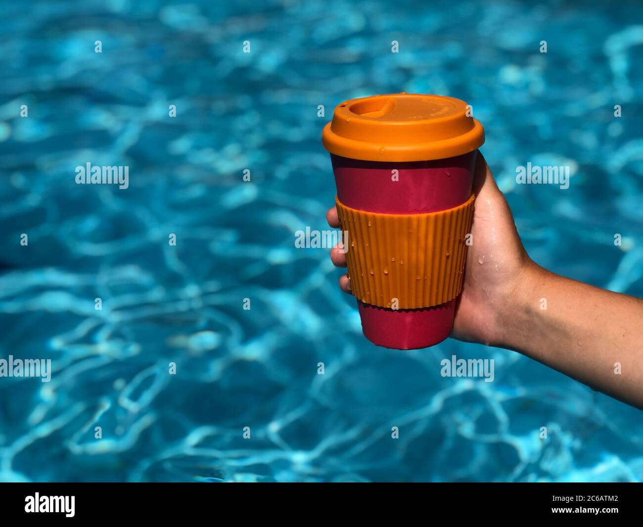 Woman enjoying coffee in a reusable bamboo mug at the swimming pool ...