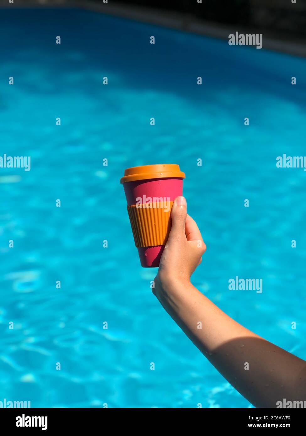 Woman enjoying coffee in a reusable bamboo mug at the swimming pool ...