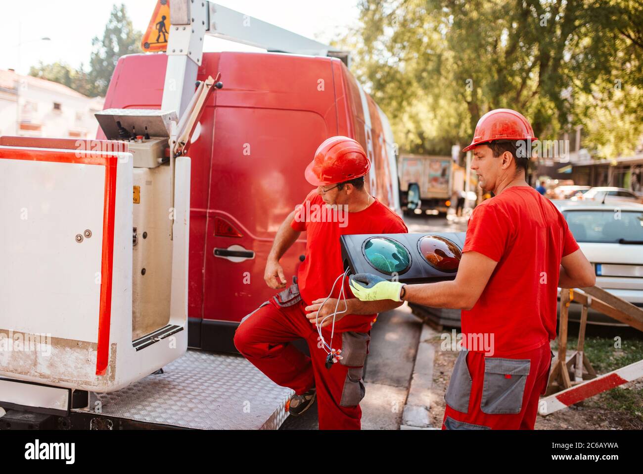 A middle-aged caucasian worker in a red uniform and helmet passes a ...