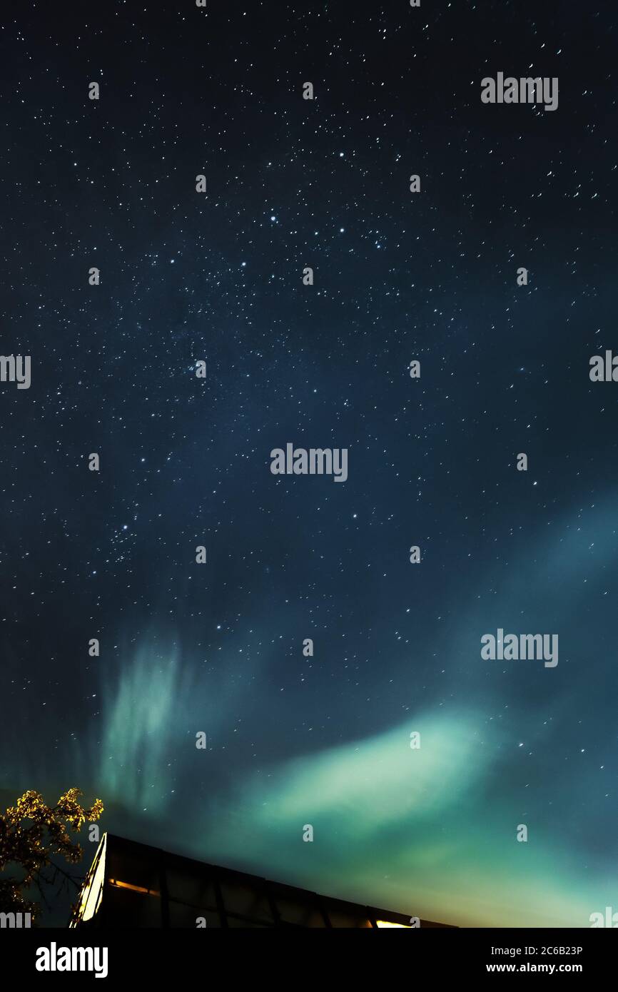Astrophotography - the northern lights and stars above the roof of the ...