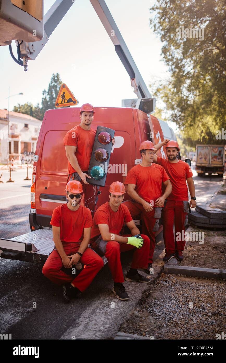 Five construction caucasian workers in red work suits stand next to a ...