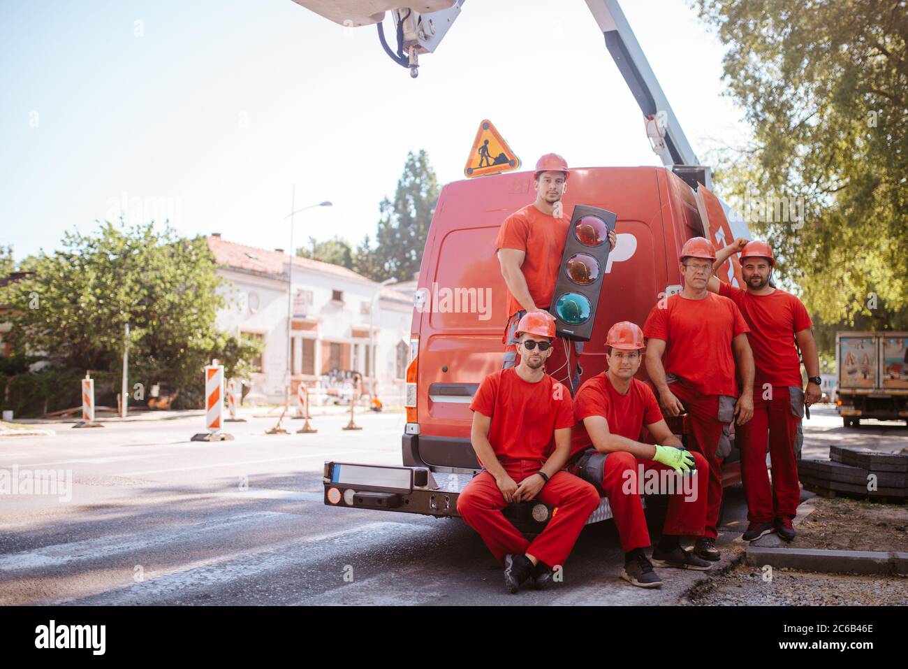 Five construction caucasian workers in red work suits stand next to a ...