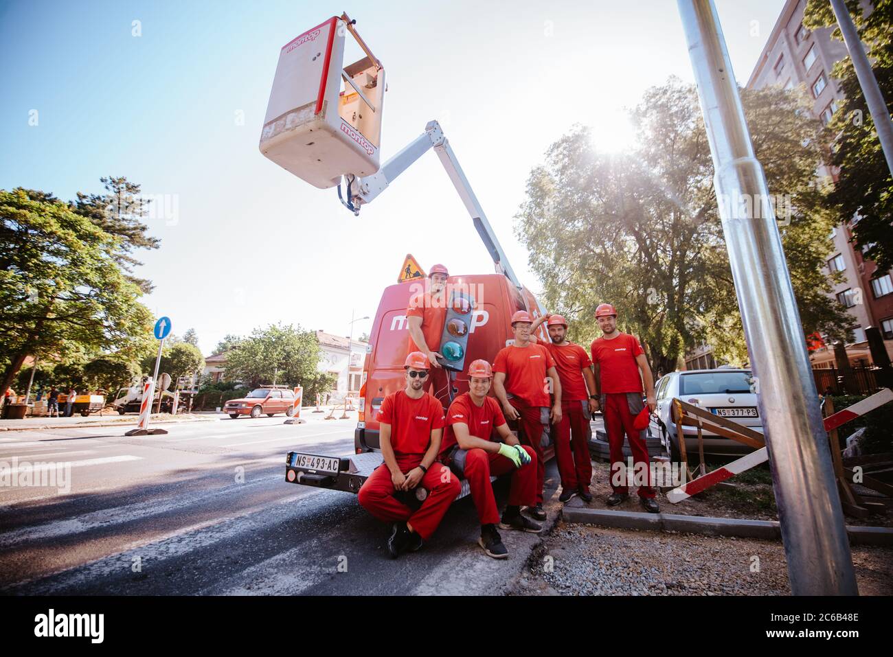 Six construction caucasian workers in red work suits stand next to a ...