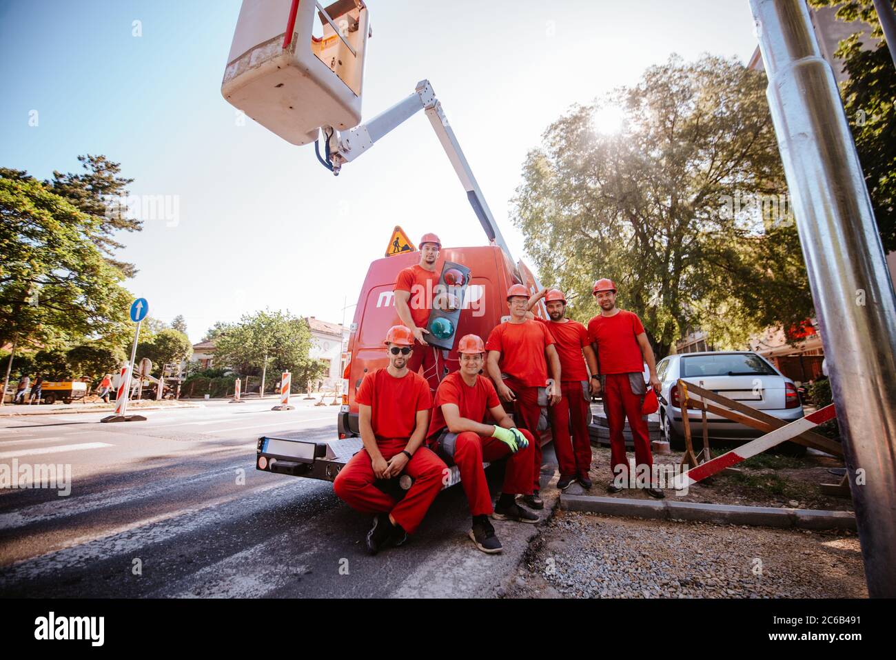 Six construction caucasian workers in red work suits stand next to a ...