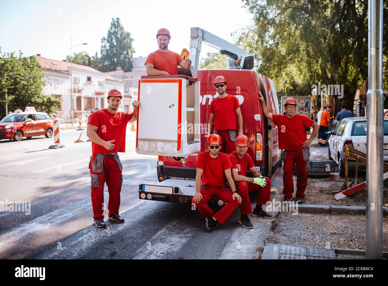 Six construction caucasian workers in red work suits stand next to a ...