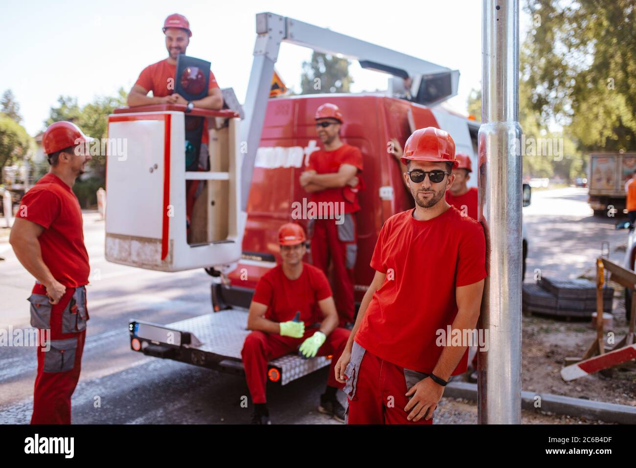 Five construction caucasian workers in red work suits stand next to a ...