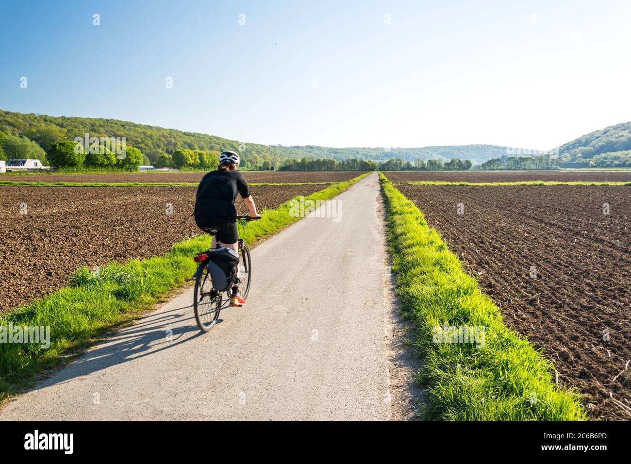 Cyclist on a bike lane in rural landscape in summer Stock Photo - Alamy
