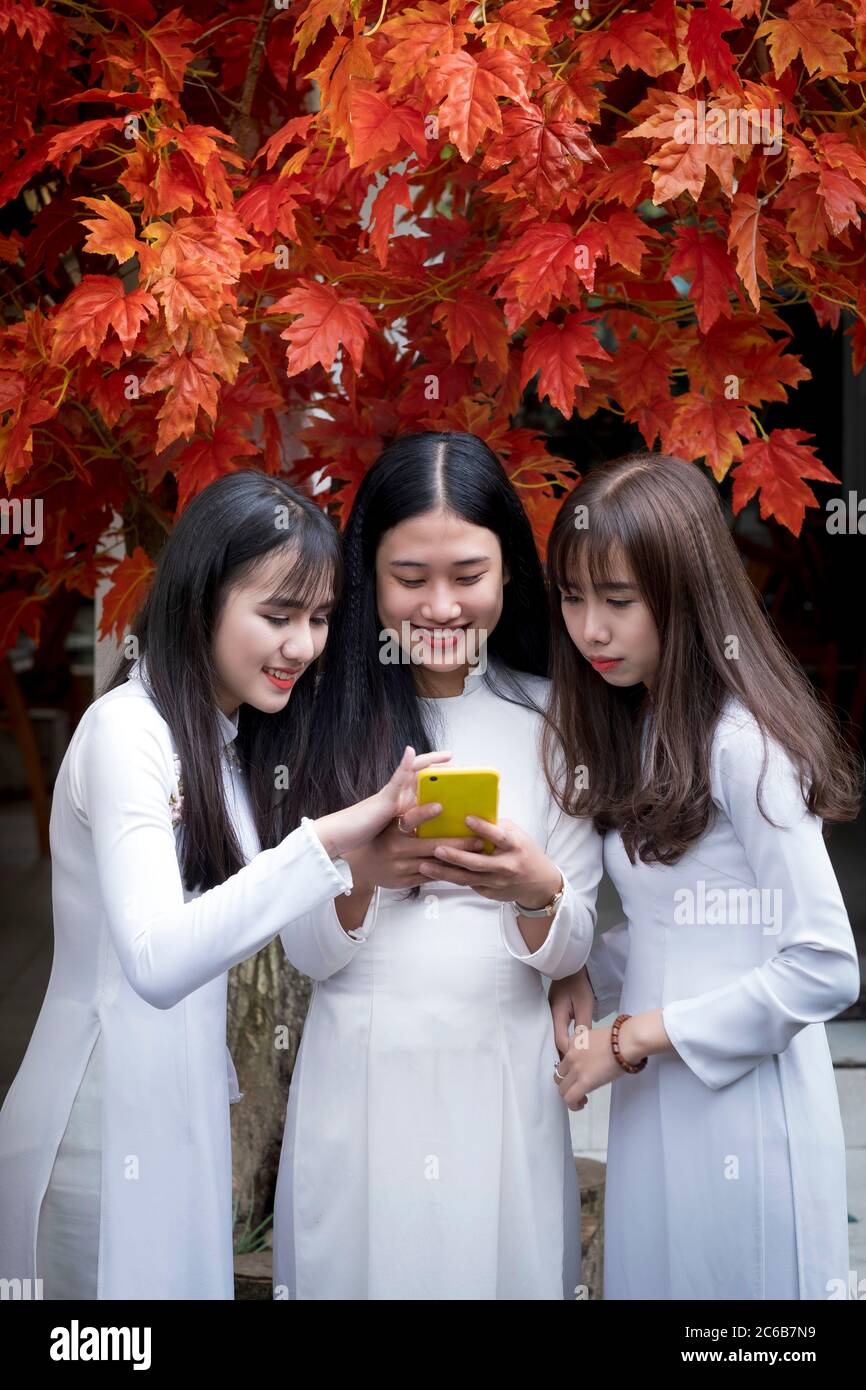 Three Vietnamese female friends wearing traditional Ao Dai dresses and ...