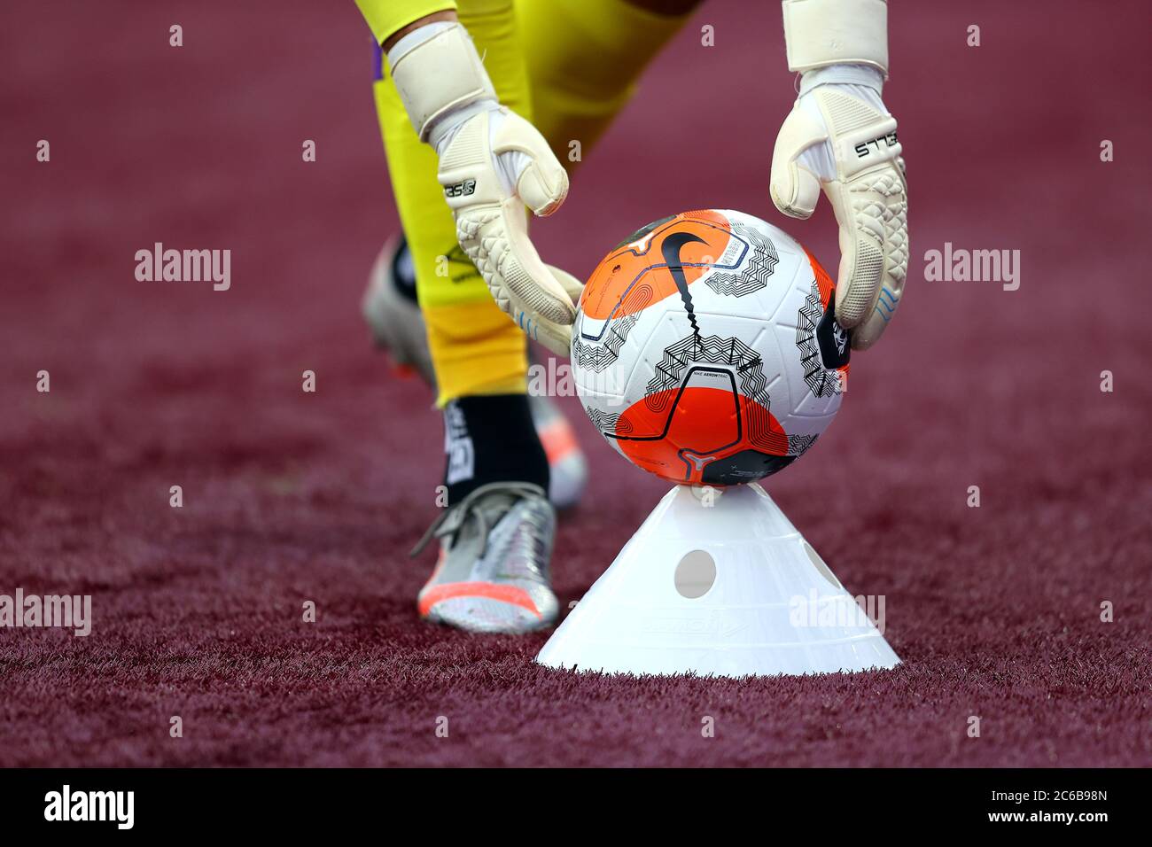 A goalkeeper collects a disinfected match ball from a cone pitch side ...