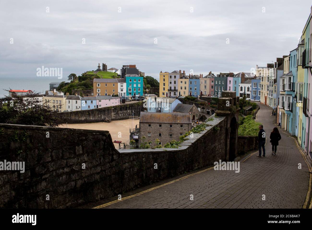 A couple walk through the narrow streets of Tenby, Pembrokeshire, Wales ...