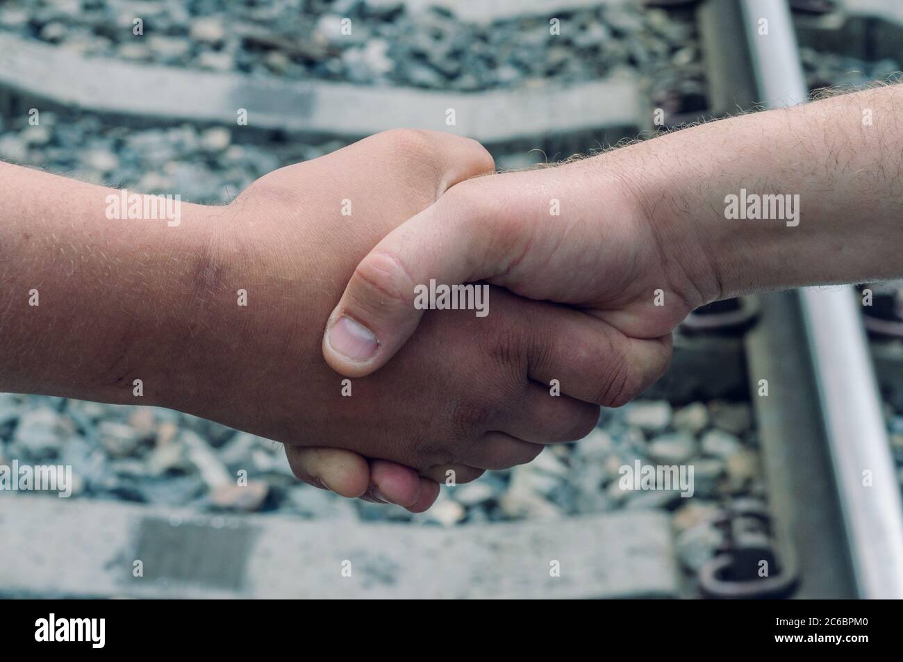 Male handshake close-up on the background of the railway. Greeting two ...