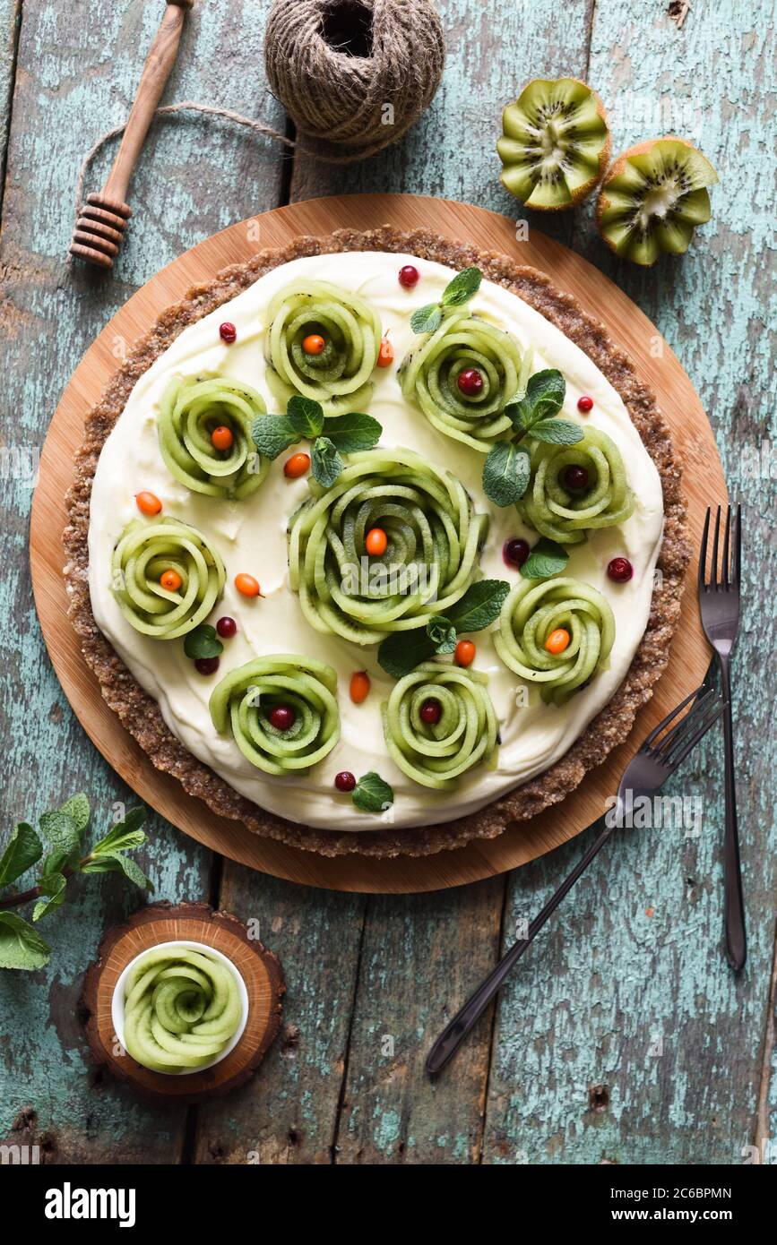 Raw vegetarian healthy dessert. Homemade pie with kiwi roses, berries ...