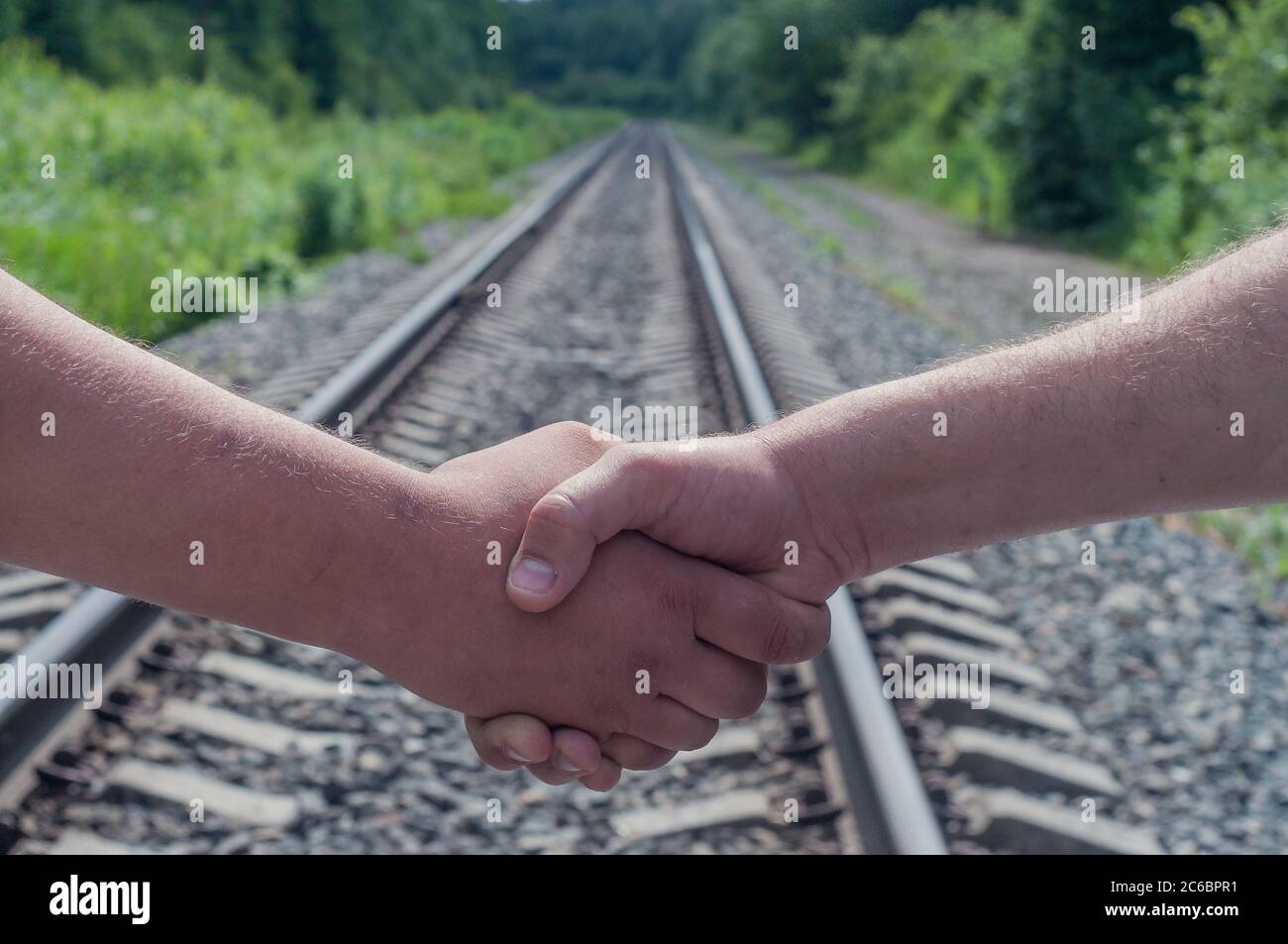 Male handshake close-up on the background of the railway. Greeting two ...