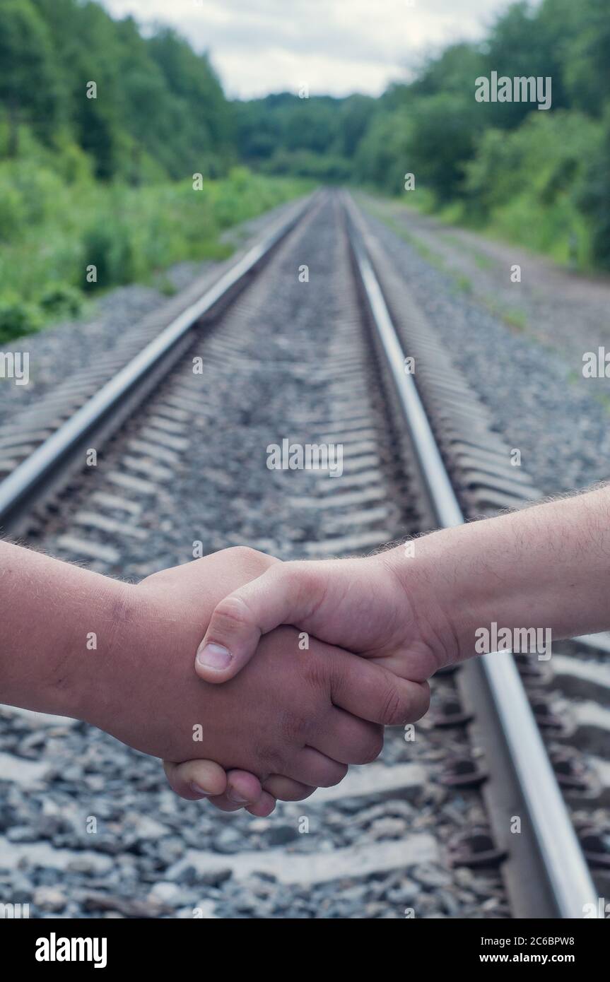 Male handshake close-up on the background of the railway. Greeting two ...
