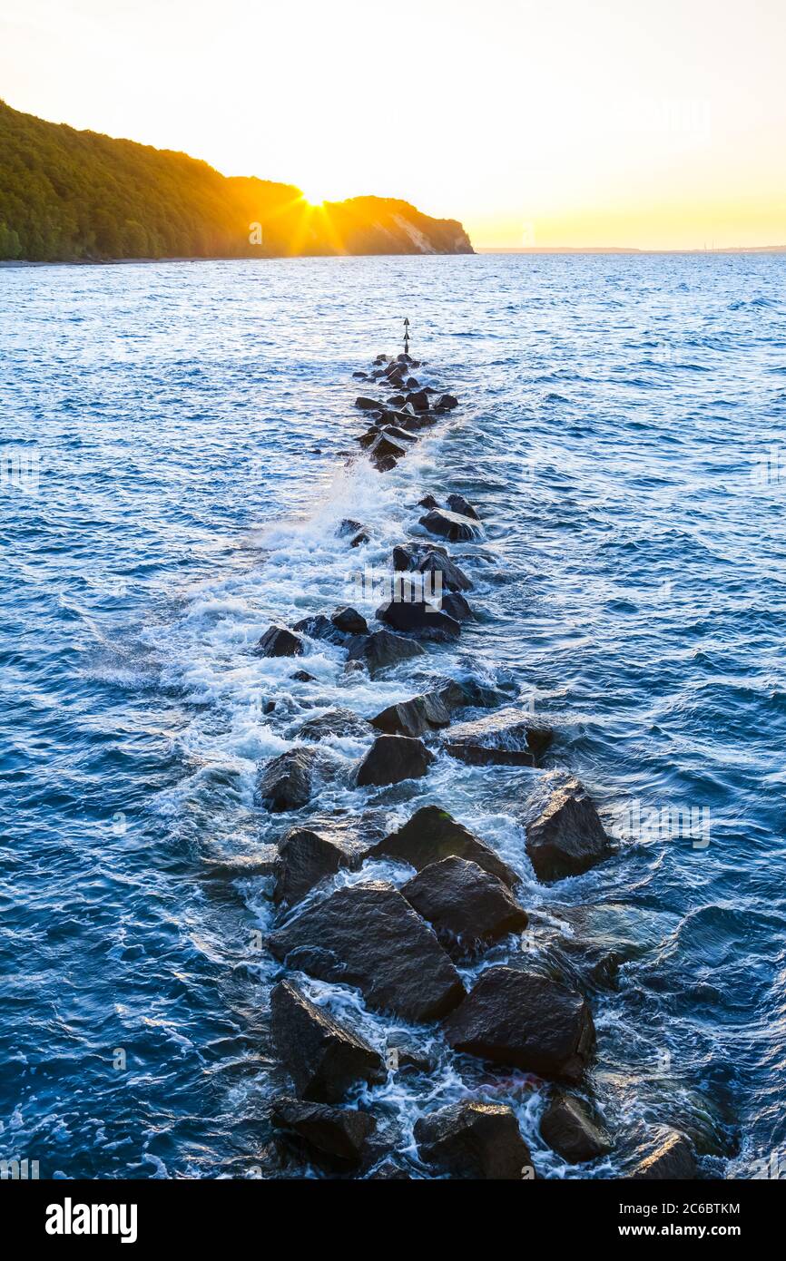 Breakwater barrier of stones with warning sign near coast - sunset sky ...