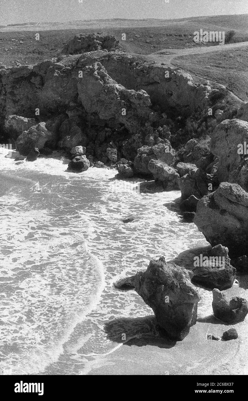 Black and white seascape. Empty rocky beach and calm sea grainy black ...