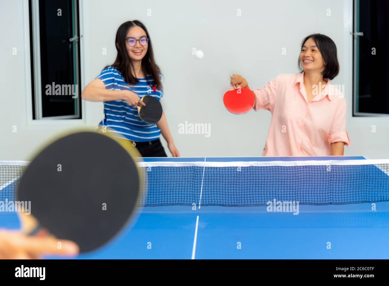 Asian family fun playing table tennis or Ping pong indoor together ...