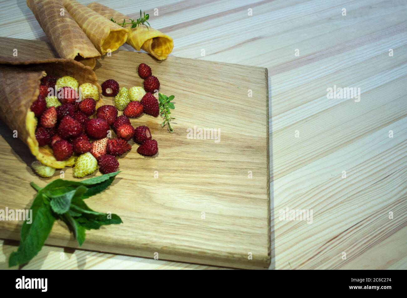 Golden waffle cone filled with strawberries and three waffle tubes ...
