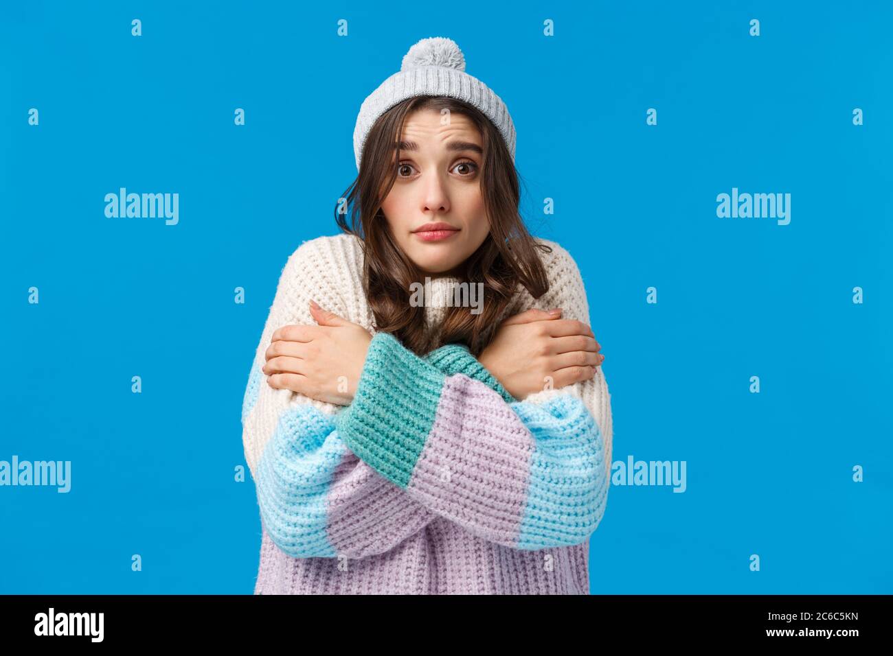 Silly timid cute caucasian brunette girl in sweater and winter hat ...
