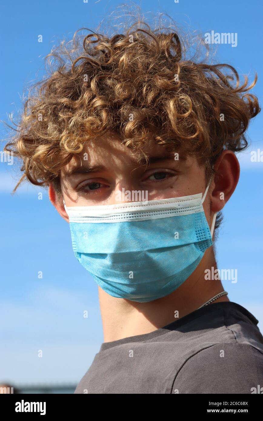 Young blond man wearing a disposable blue face mask, portrait Stock ...