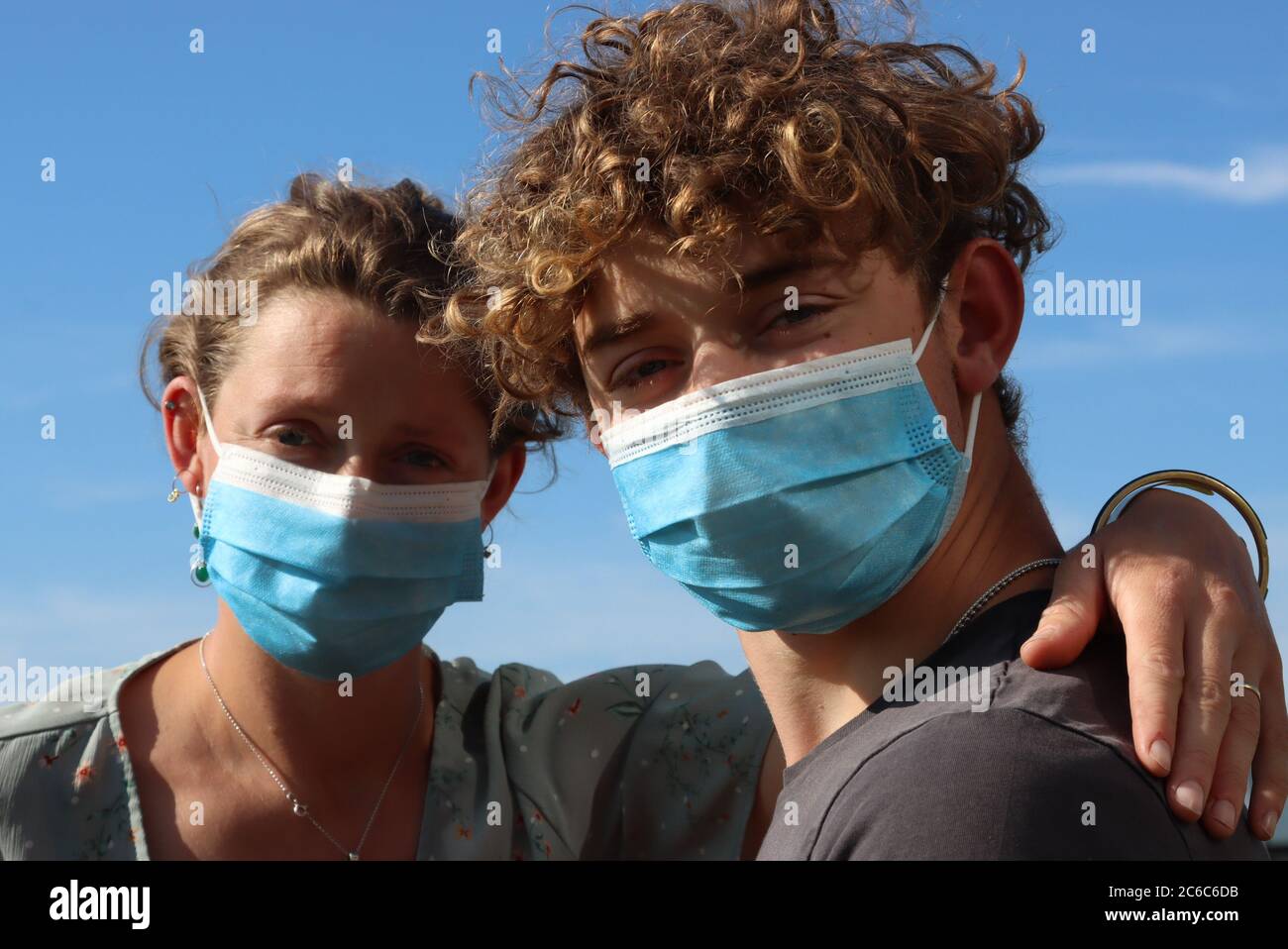 Girl and boy wearing disposable face masks with a clear blue sky in the ...
