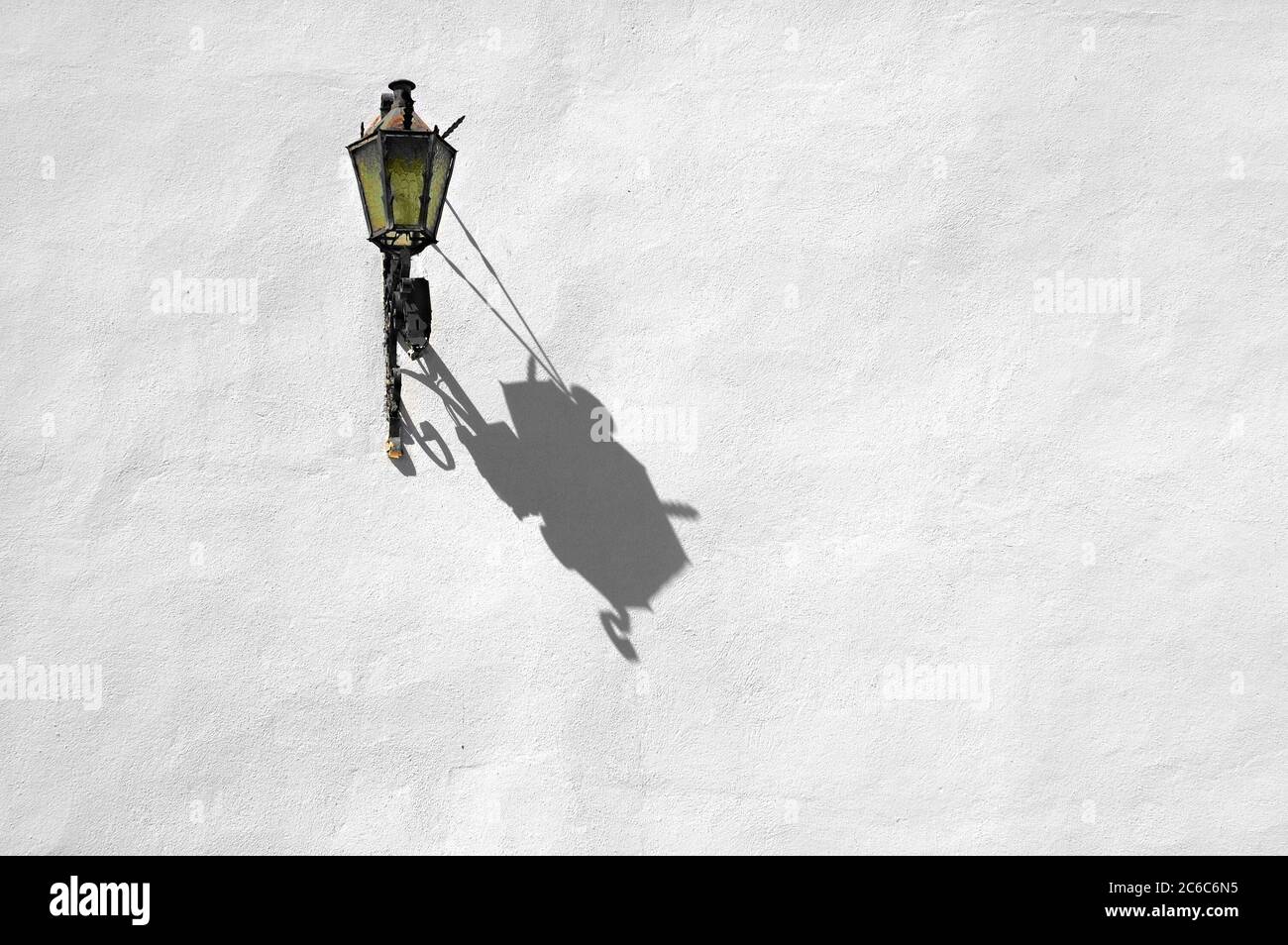 Medieval street lamp and its shadow on the white plastered wall. Ronda ...