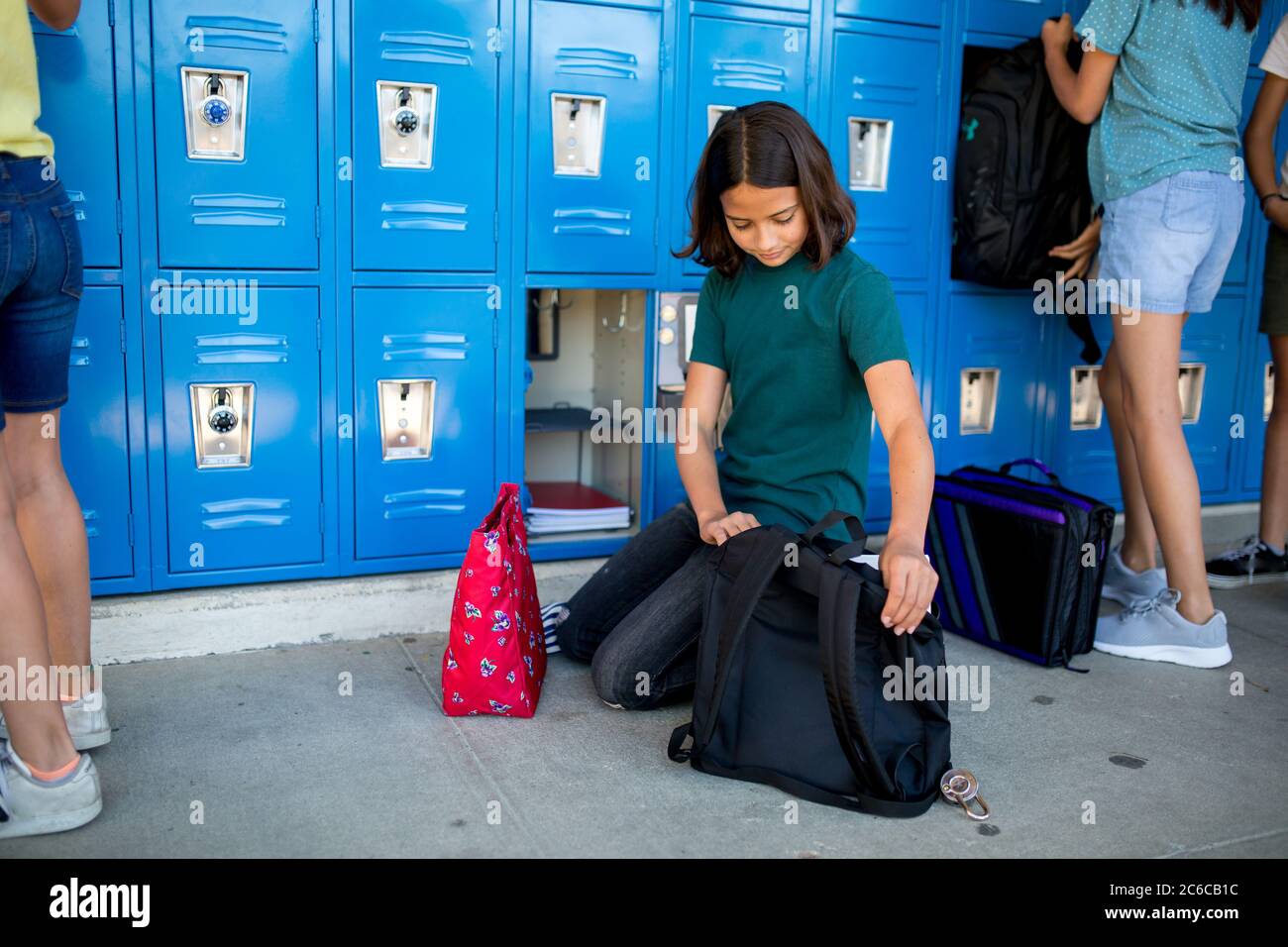 Tween girl looks into her backpack as she organizes her locker Stock ...