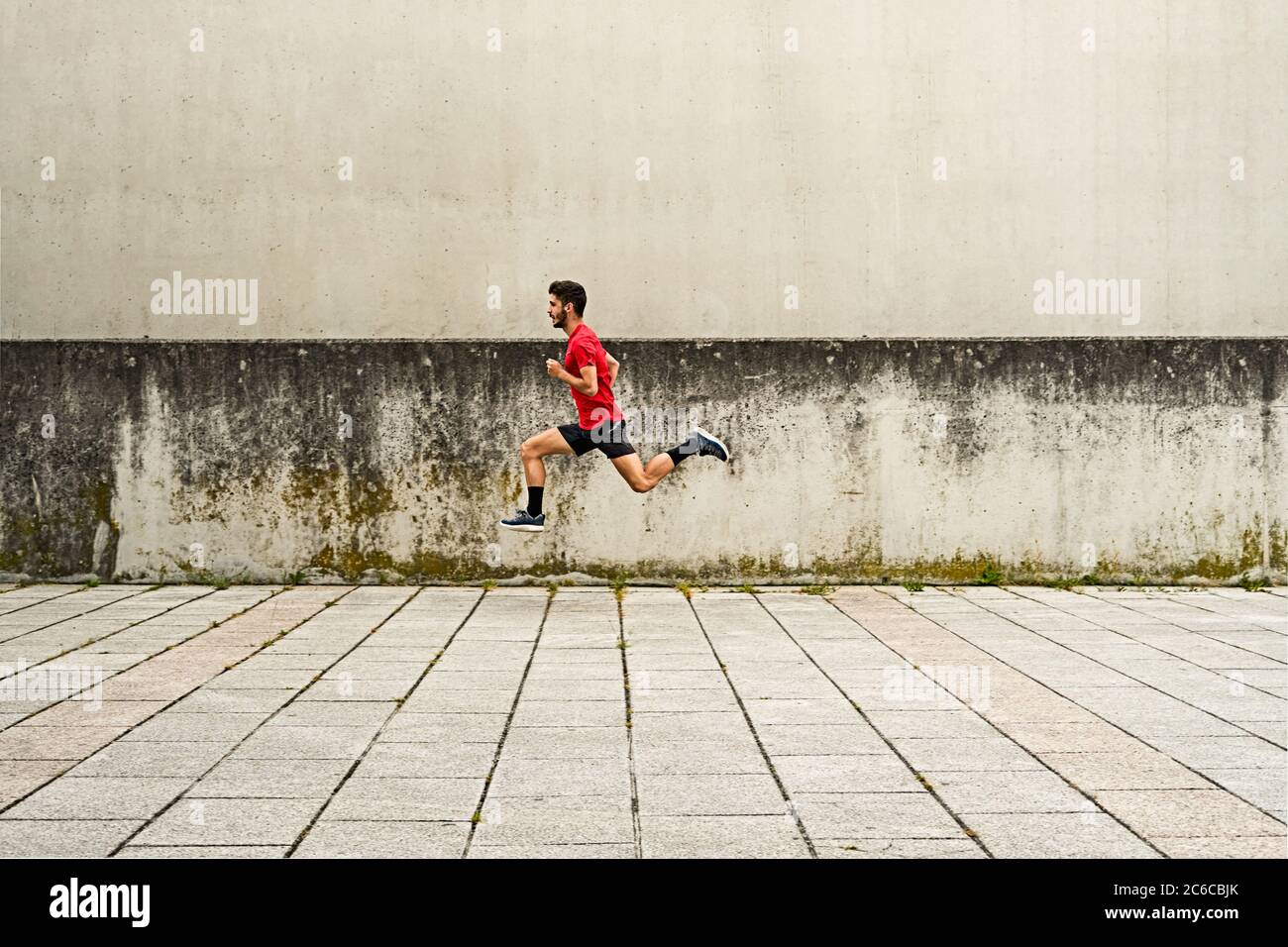 young man running in a red shirt and black pants through the park Stock ...