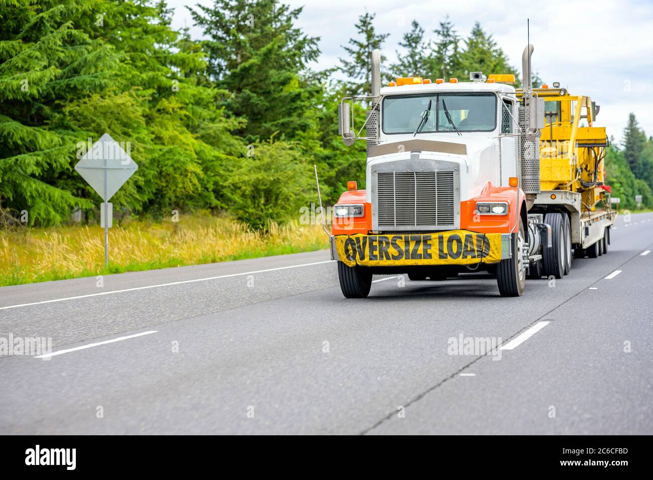 Powerful big rig semi truck with orange fenders ang oversize load sign ...