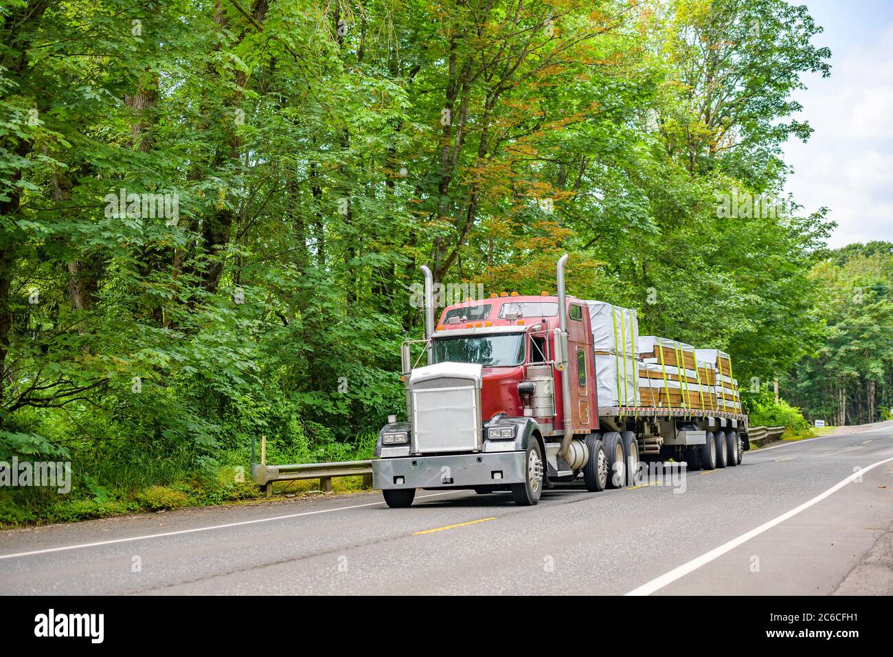 Big rig red classic semi truck with vertical exhaust pipes transporting ...