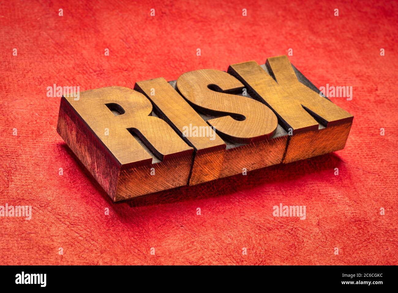 risk word in vintage letterpress wood type against red textured paper ...