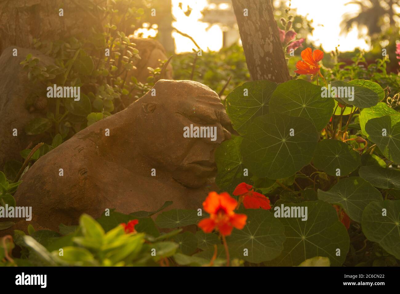 Ogre statue in a garden. Rustic sculpture of an ogre in the undergrowth ...