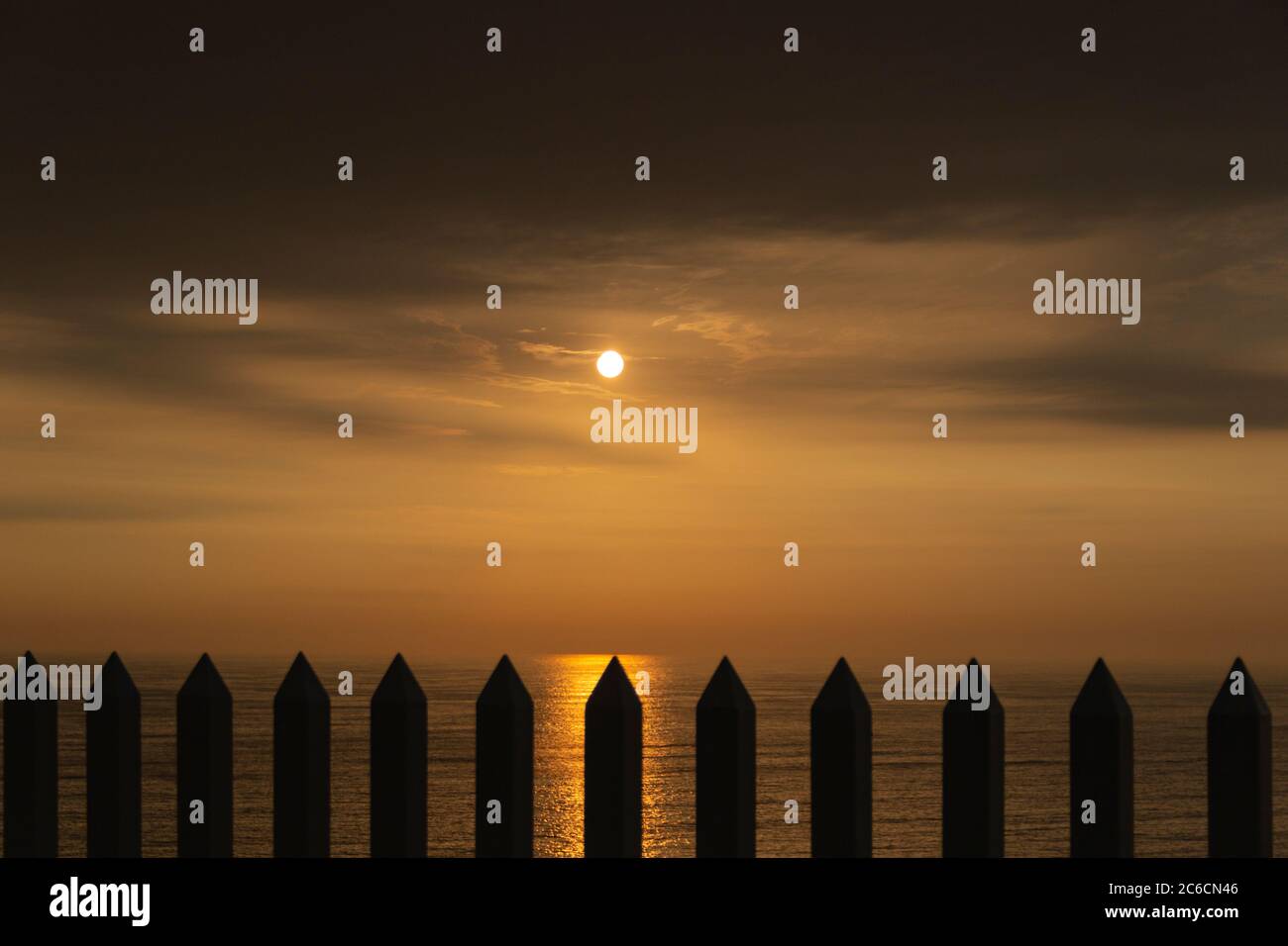 Sun behind the bars of a fence. Sunset with the sun on the horizon ...