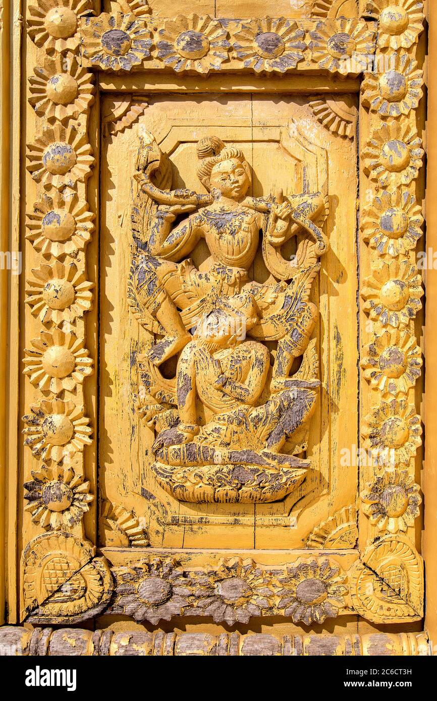 A close-up detail of wood carvings on a door panel of an ancient temple ...